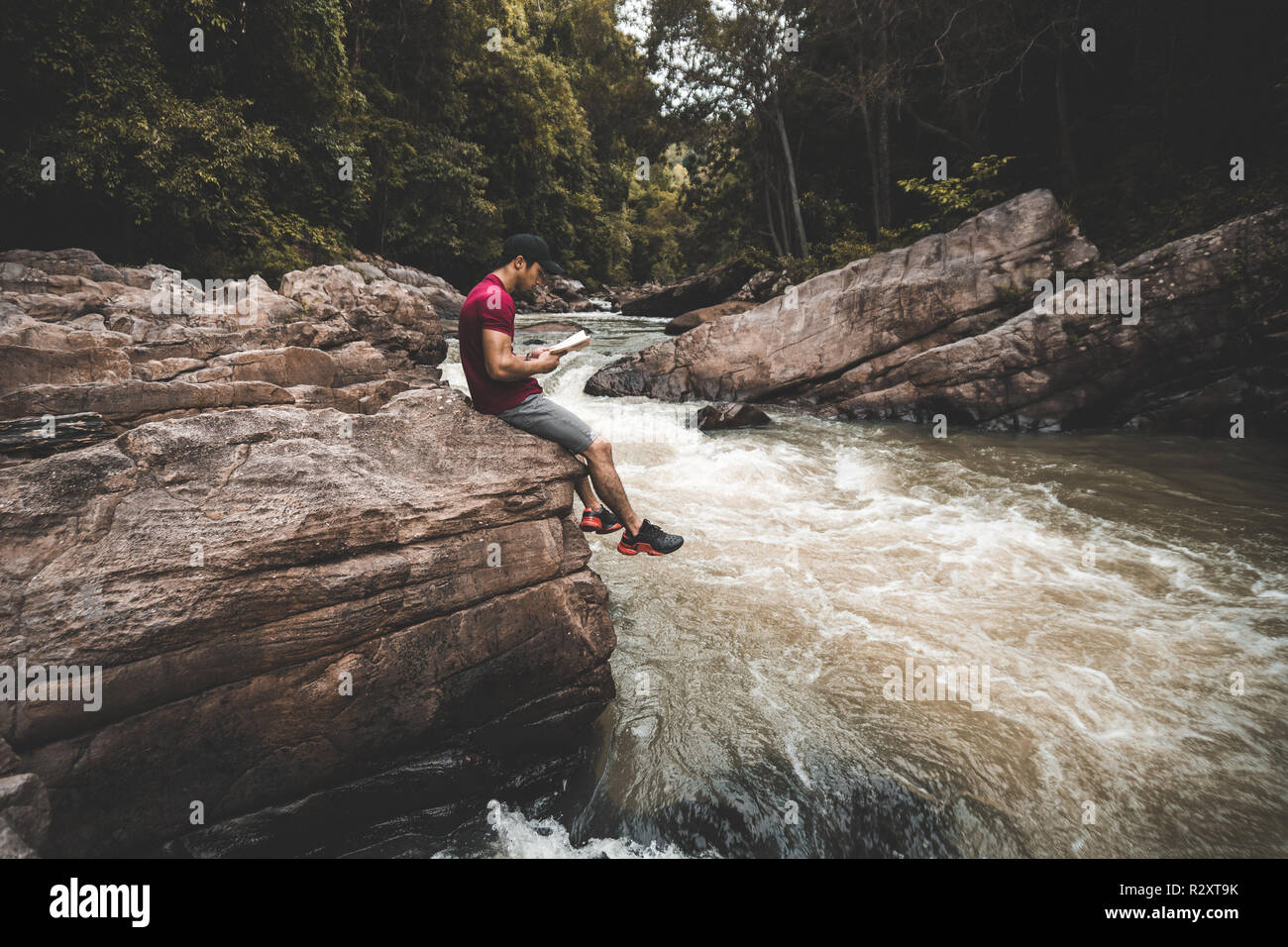 Adventurer guy spending his time reading a book at the edge of huge ...