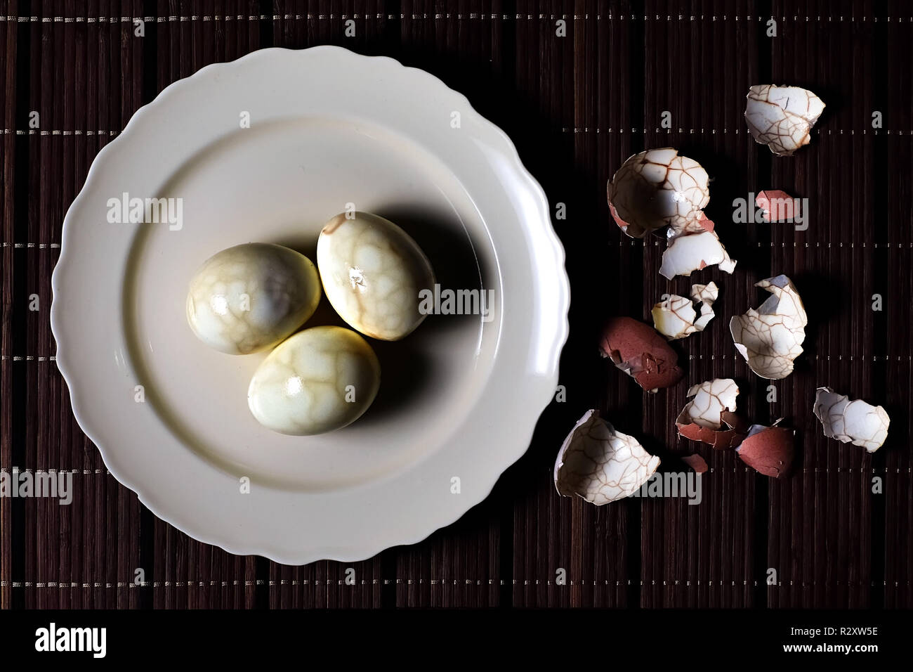 Tea marble duck eggs on white plate nad dark bamboo background top view ...