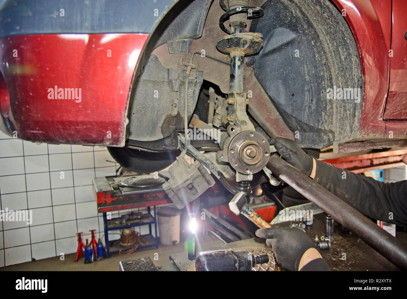 The mechanic in the workshop replaces the bearing on the front axle of ...