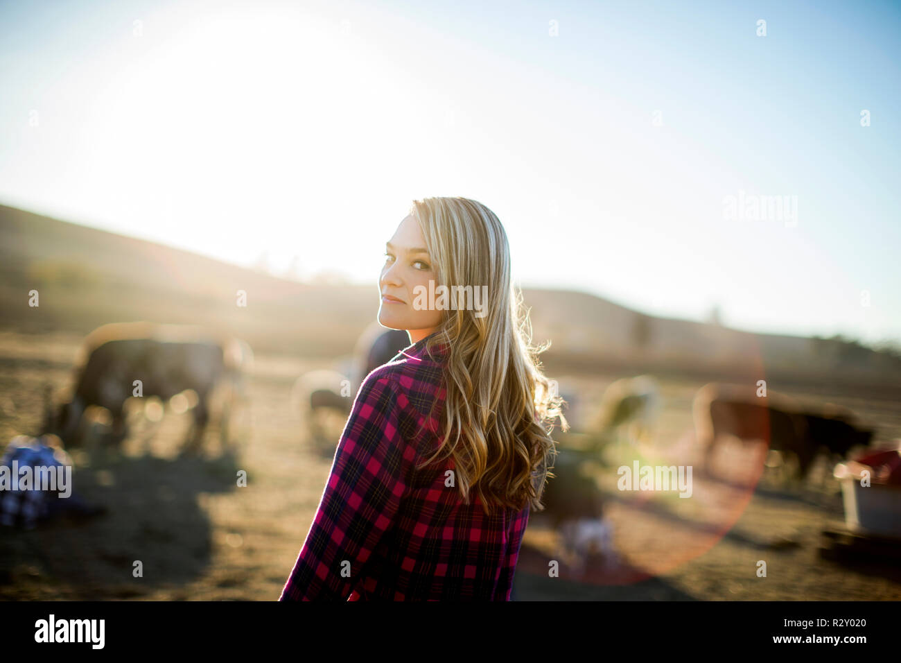 Portrait of a young cowgirl looking flirtatiously over her shoulder ...
