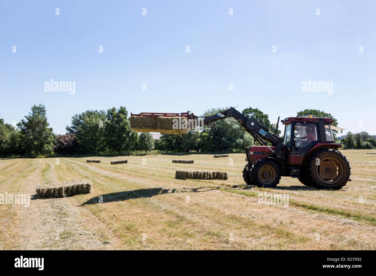 Tractor in a field, lifting stack of hay bales Stock Photo - Alamy