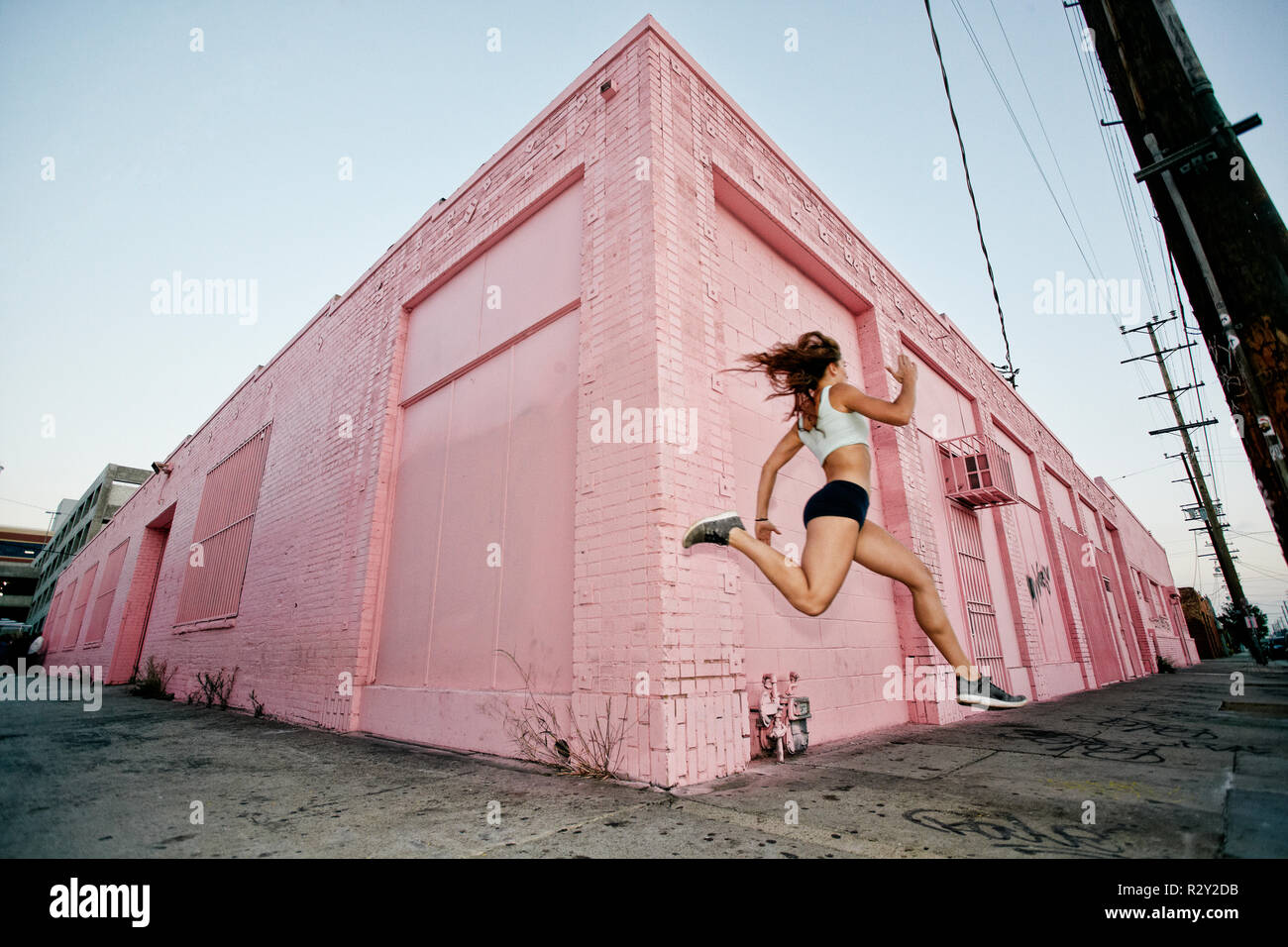 Female athlete running on sidewalk past pink building Stock Photo - Alamy