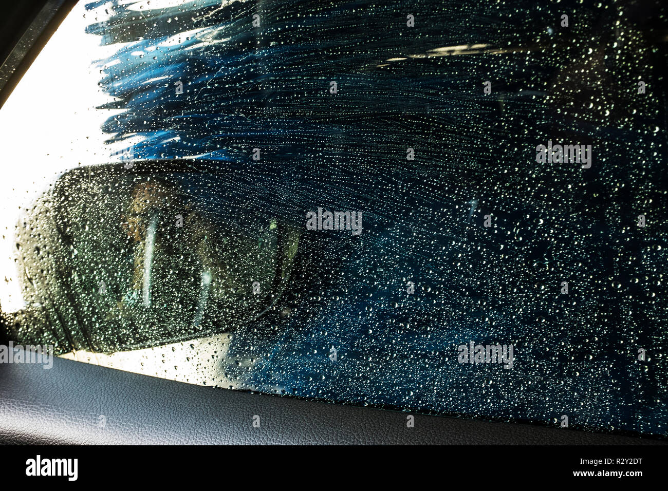 View from the inside of a car in an automated car wash, blue washers ...