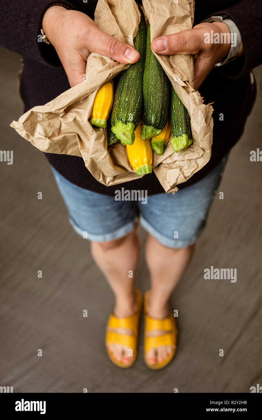 A woman holding out her hands holding a bunch of freshly picked yellow ...