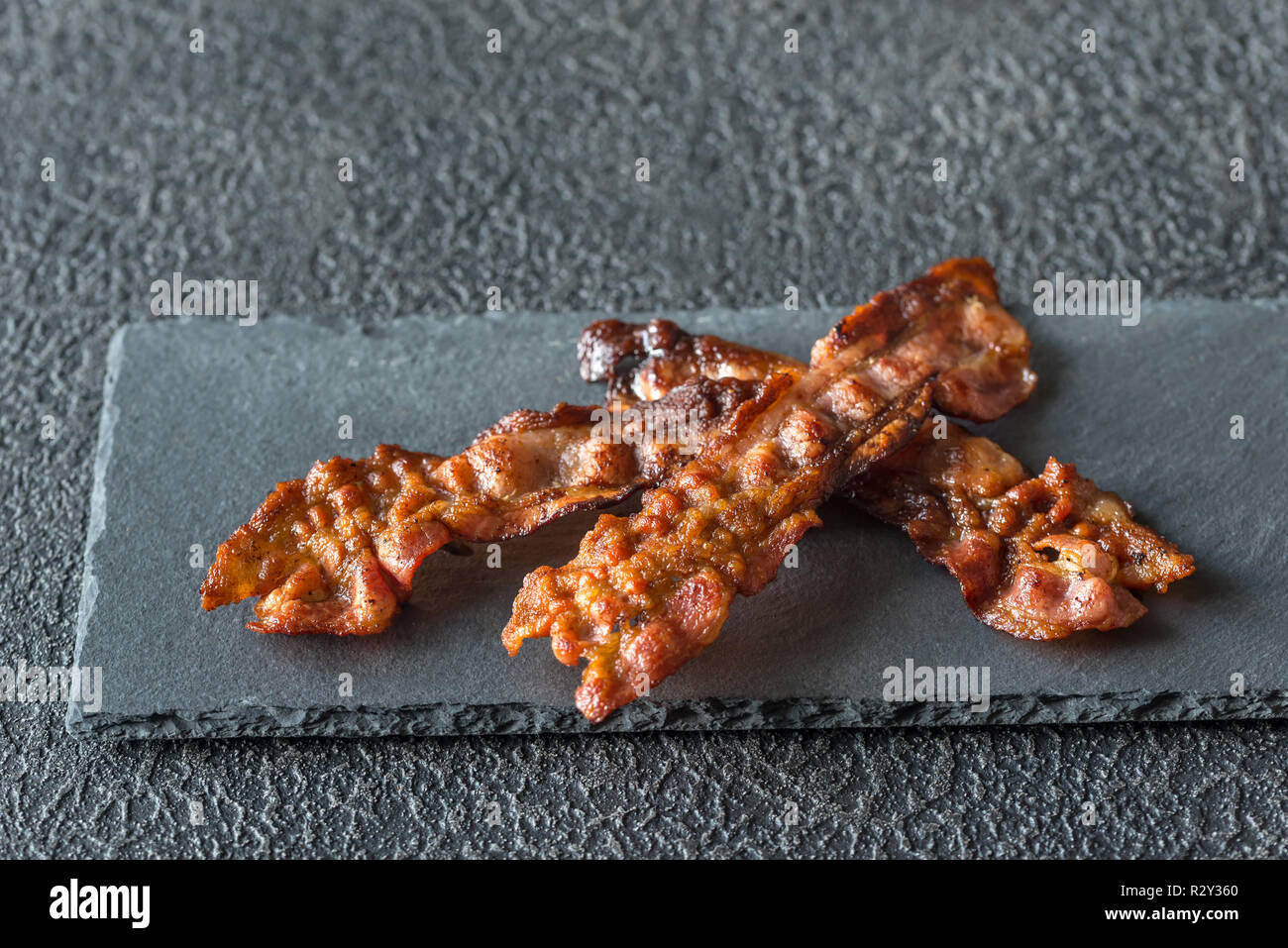 Fried bacon strips on the stone dark board Stock Photo - Alamy