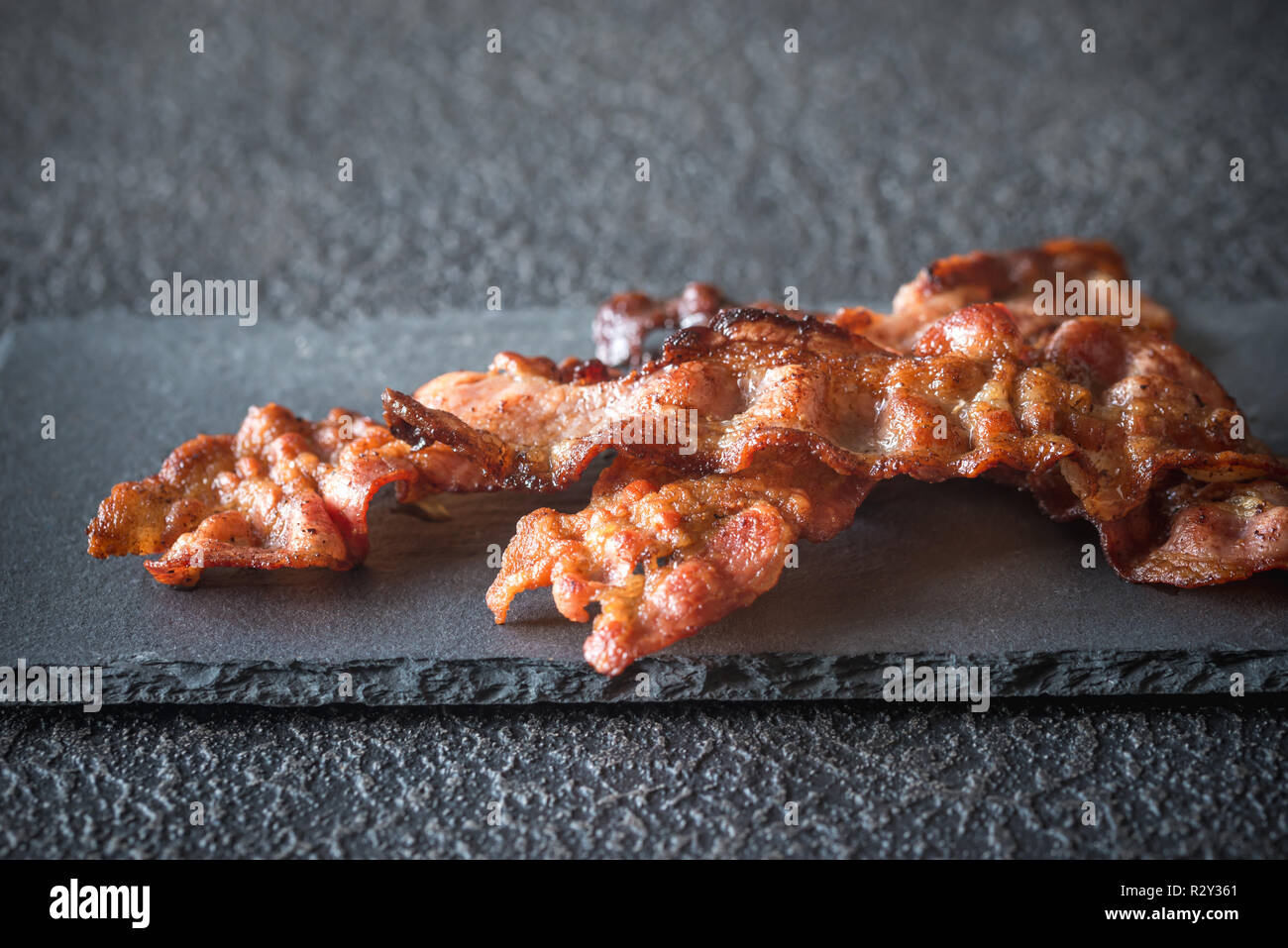 Fried bacon strips on the stone dark board Stock Photo - Alamy