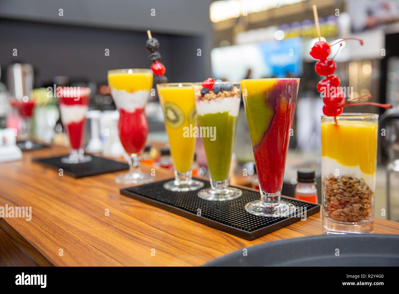 A set of different colored smoothies in glasses on wooden background ...