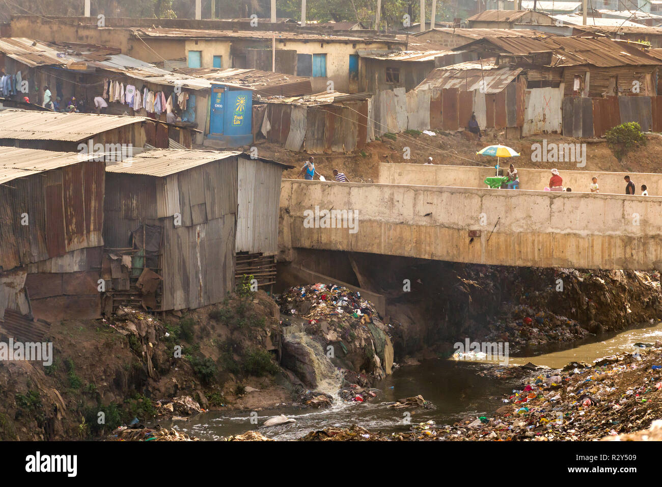 A bridge with people crossing Mathare river which is filled with ...