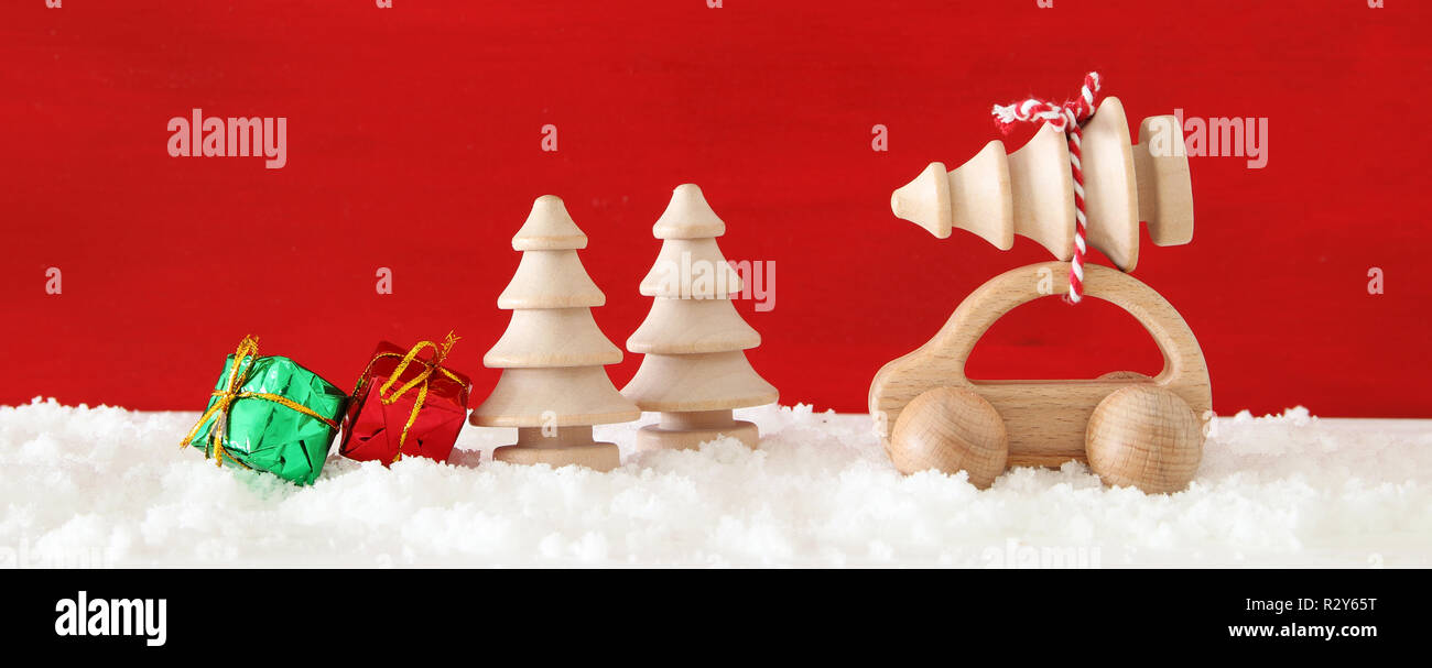 Wooden car carrying a christmas tree in front of red background Stock ...