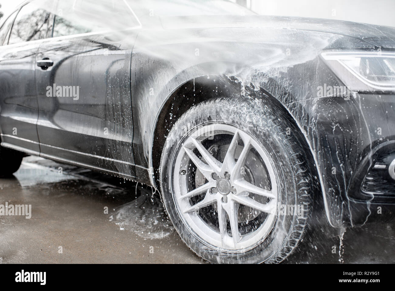 Close-up of a car under the water jet during the washing process on a ...