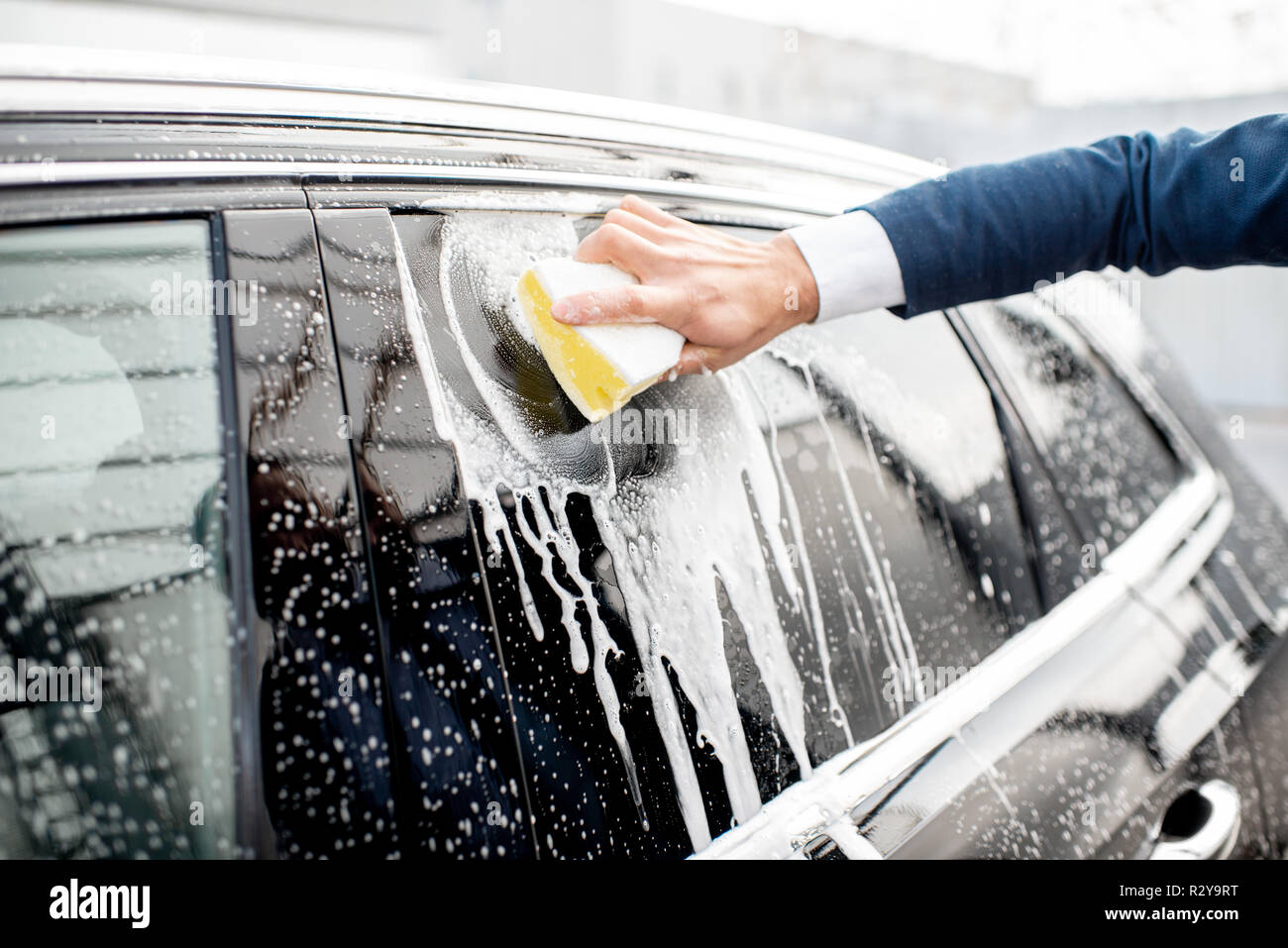 Businessman washing car window with sponge and foam on a self service ...