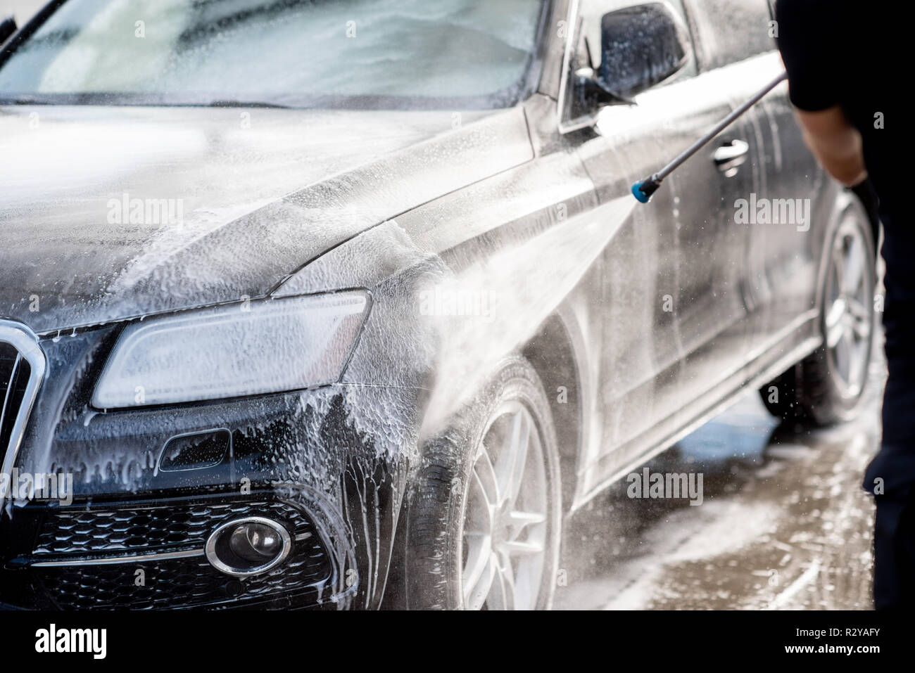 Close-up of a car under the water jet during the washing process on a ...