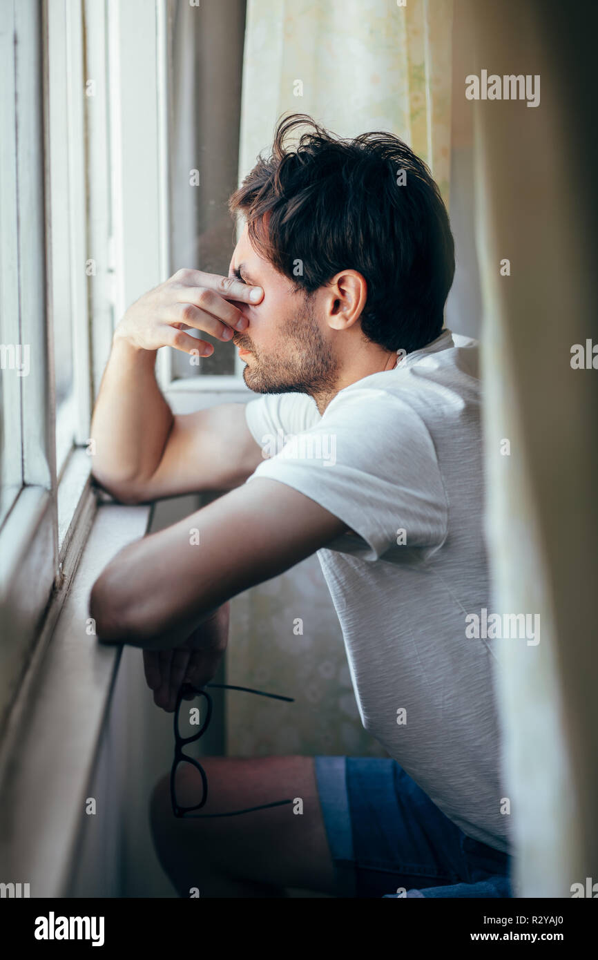 Tired young man in depression crying near window. Pain concept Stock ...