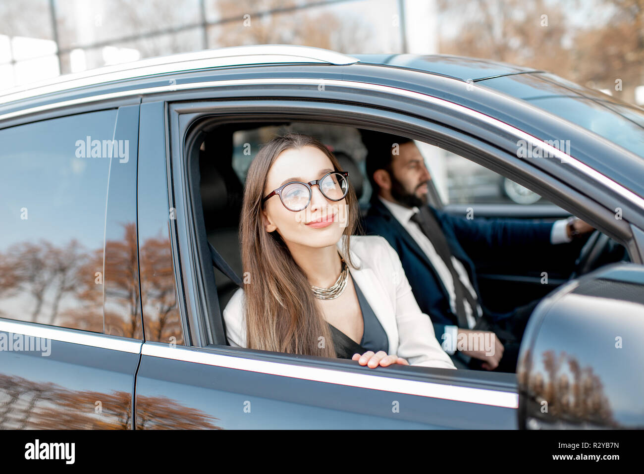 Elegant businesswoman looking out the window driving luxury car with ...