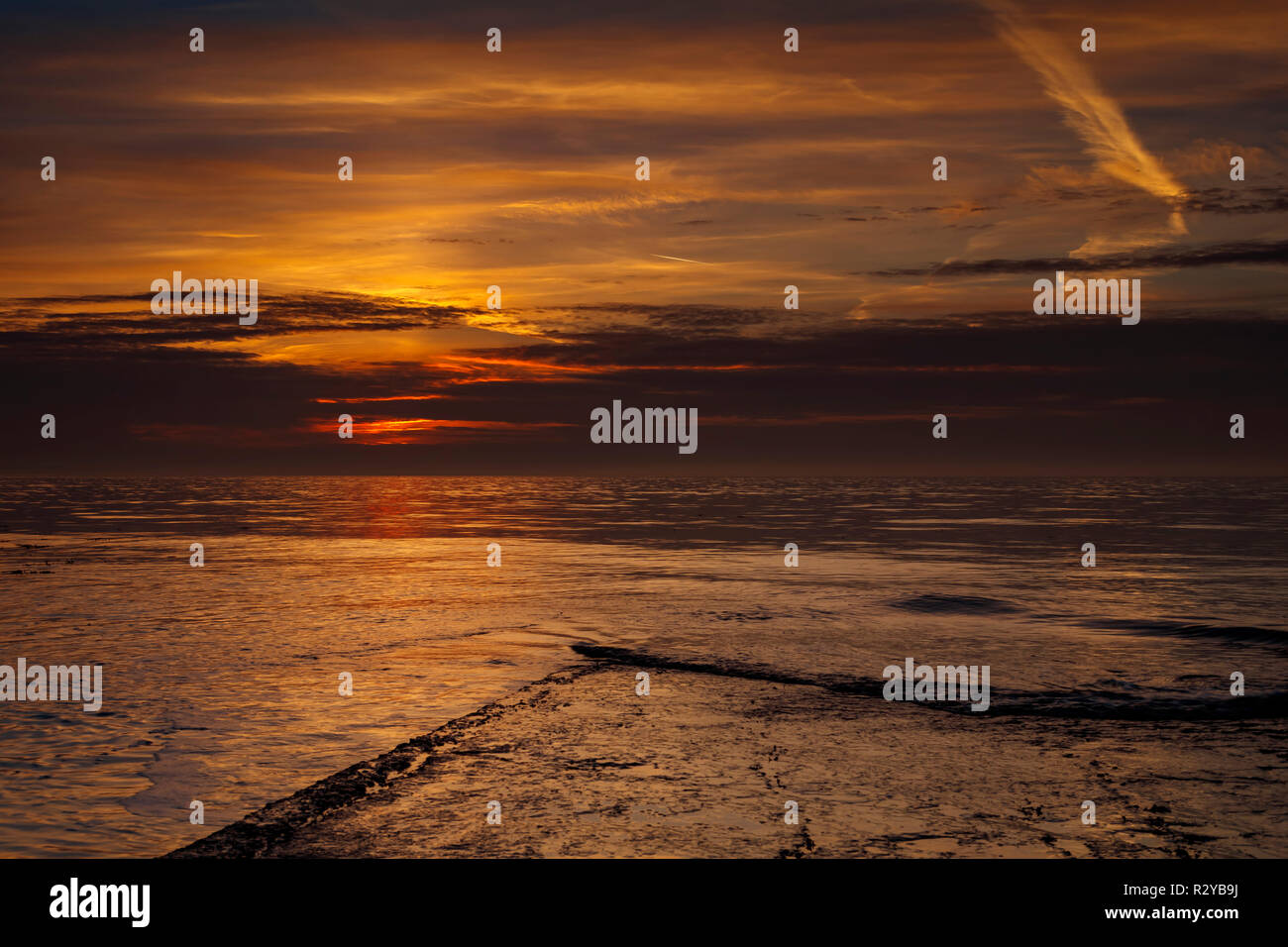 The sun setting over the horizon Stock Photo - Alamy
