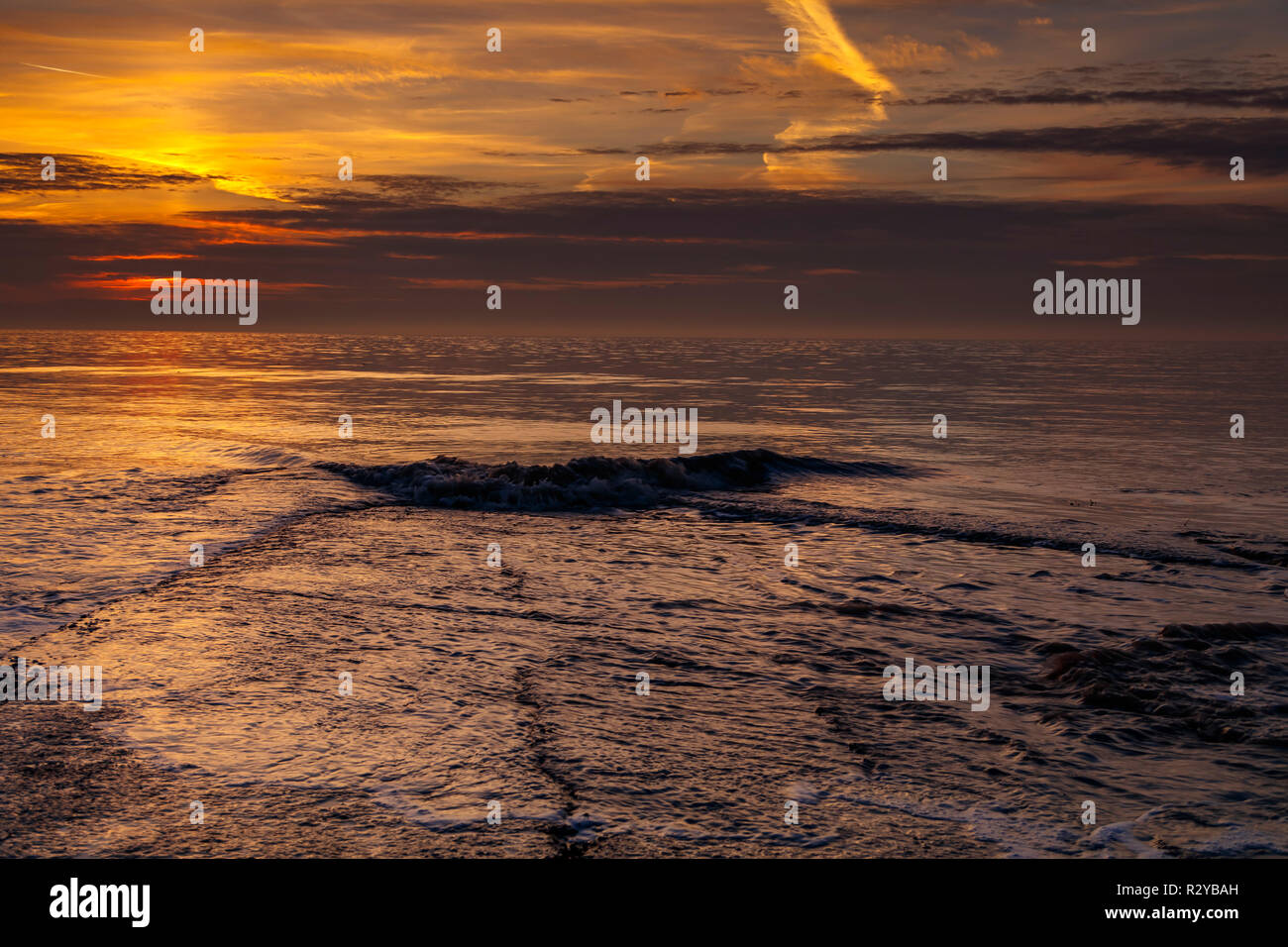 The sun setting over the horizon Stock Photo - Alamy