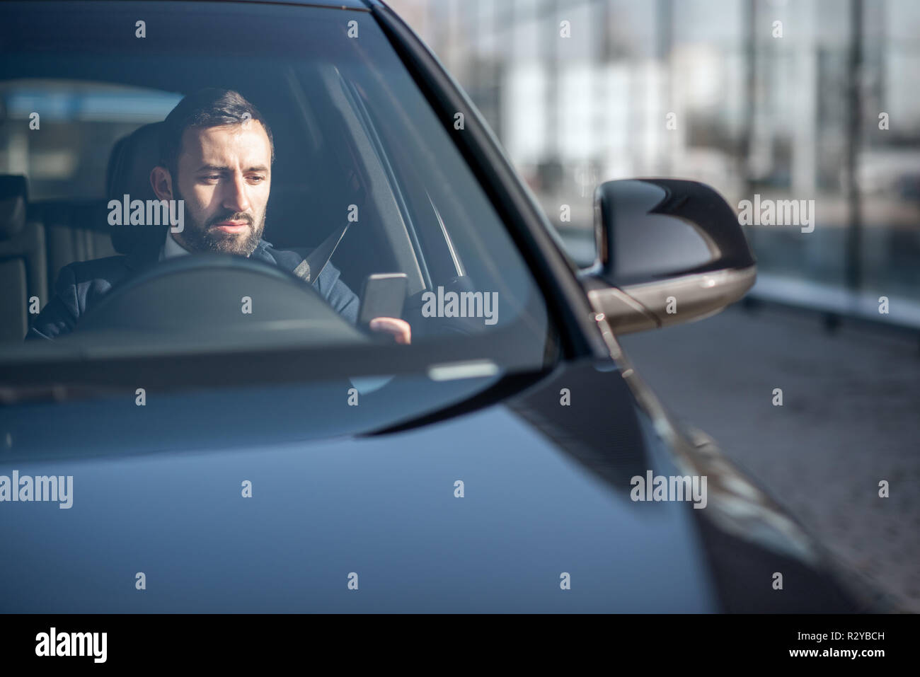 Businessman driving a luxury car, view from the outside through the ...
