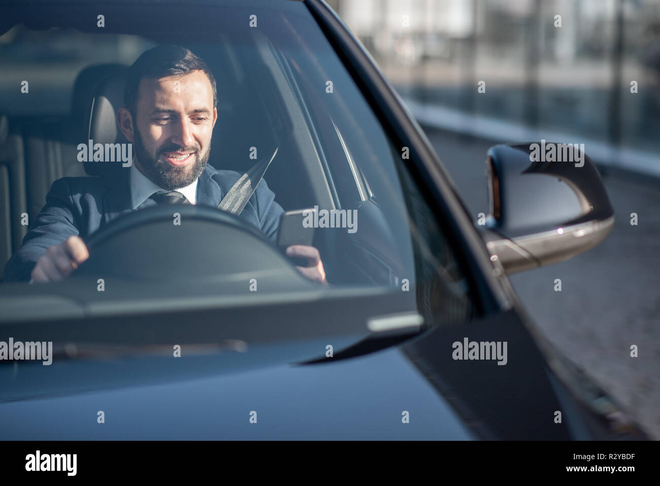 Happy businessman driving a luxury car, view from the outside through ...