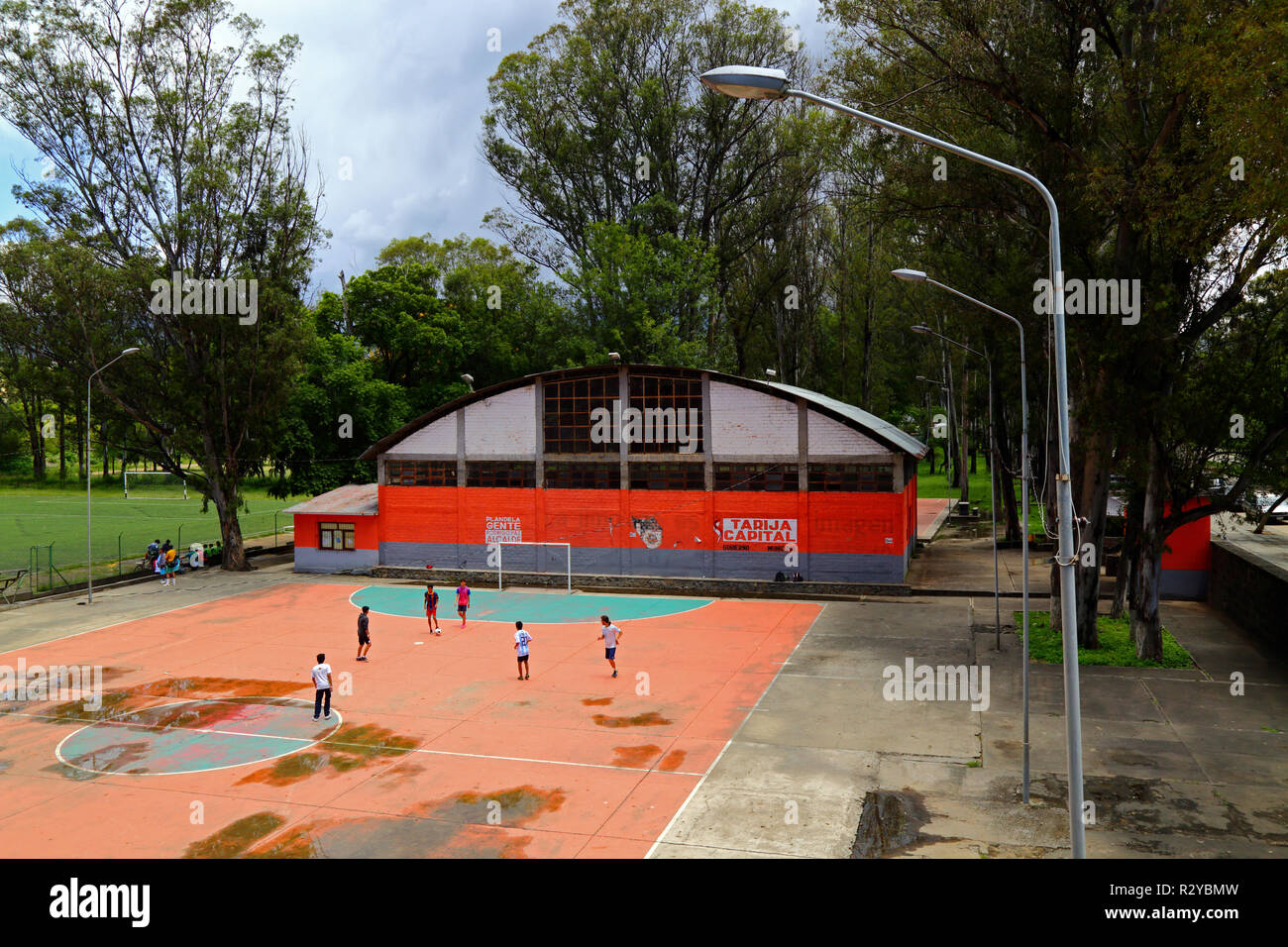Youths playing football on outdoor concrete pitch in sports centre ...