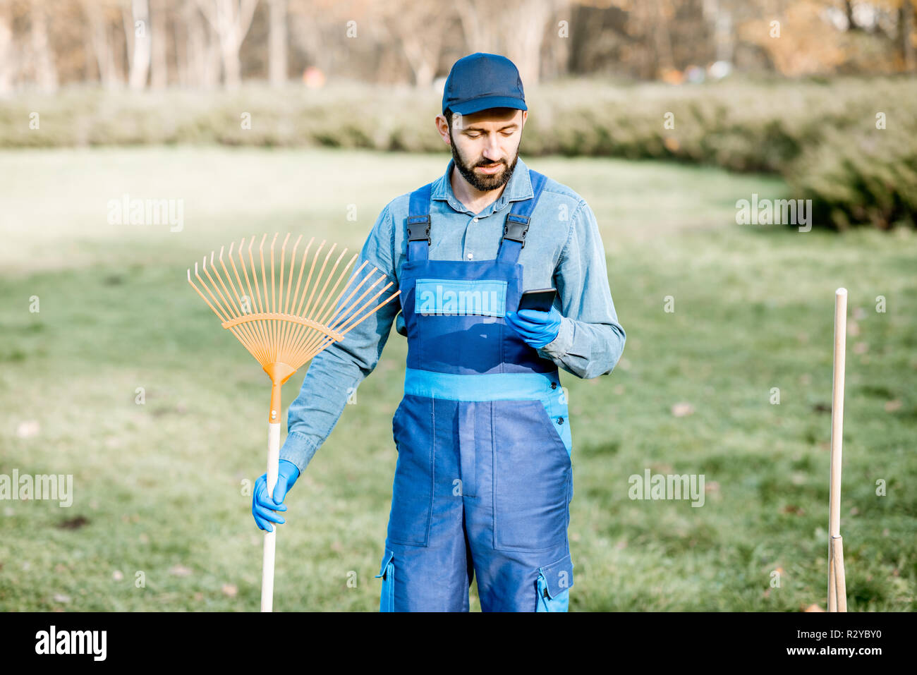 Professional sweeper in uniform using phone during the work in the ...