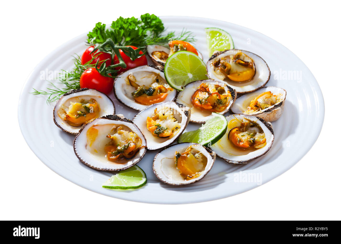 Plate of delicious oven baked clams with sauce and lime. Isolated over ...