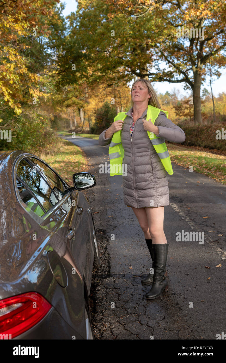 Woman motorist by her car putting on a reflective safety jacket Stock ...