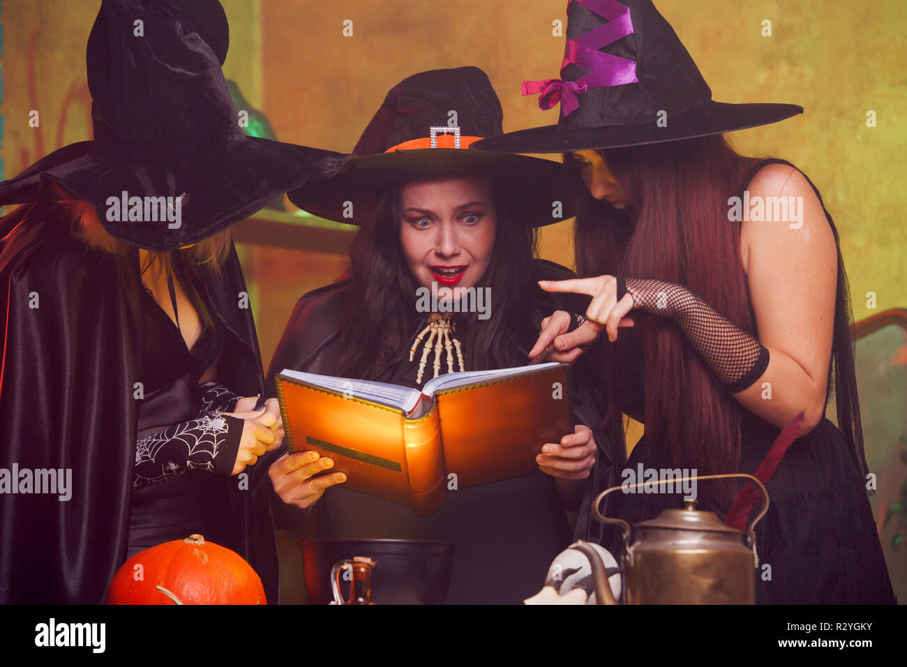 Photo of three witches with book in hands at dark room Stock Photo - Alamy