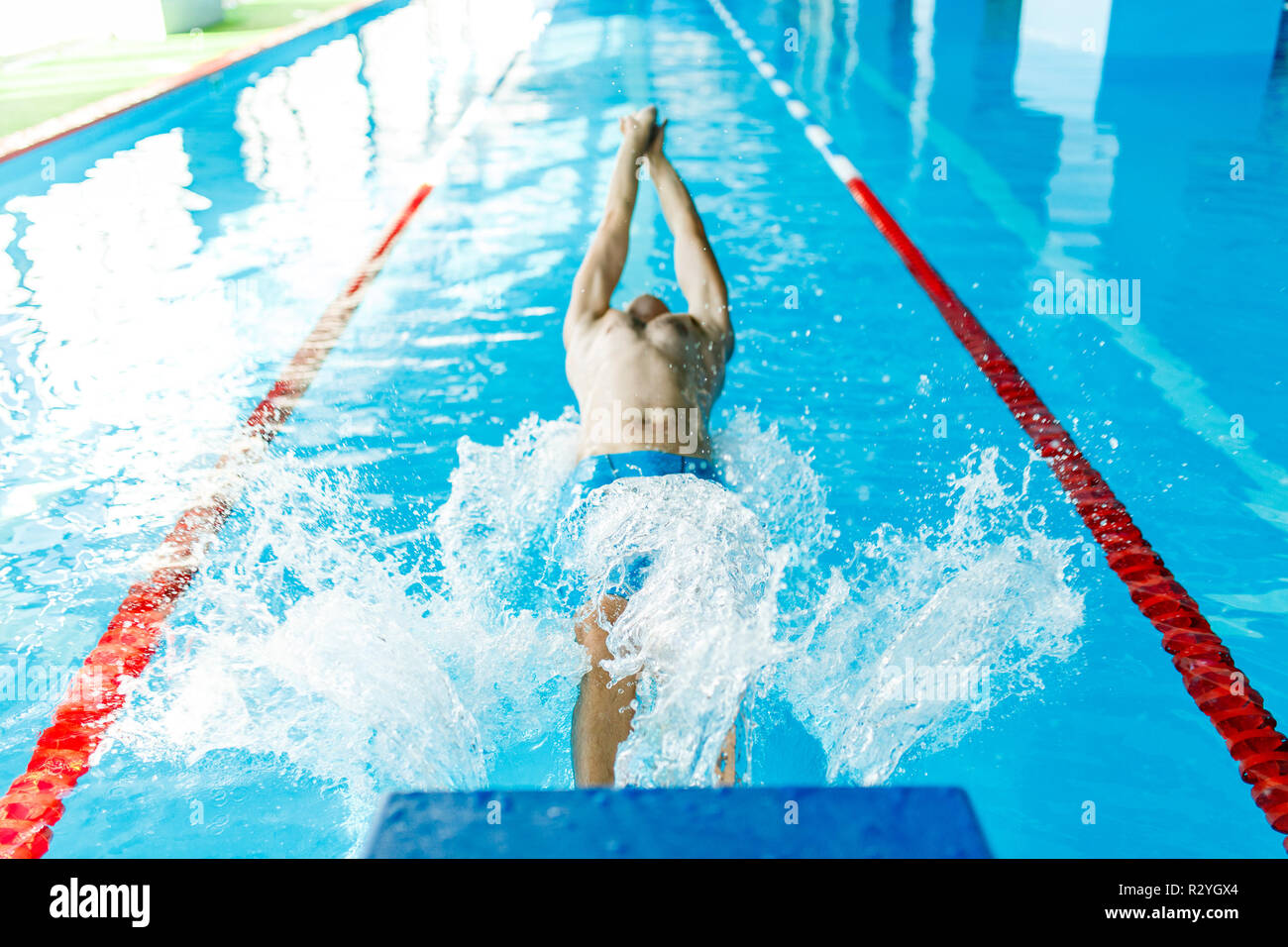Photo of athlete in blue rubber cap swimming on back in pool during ...