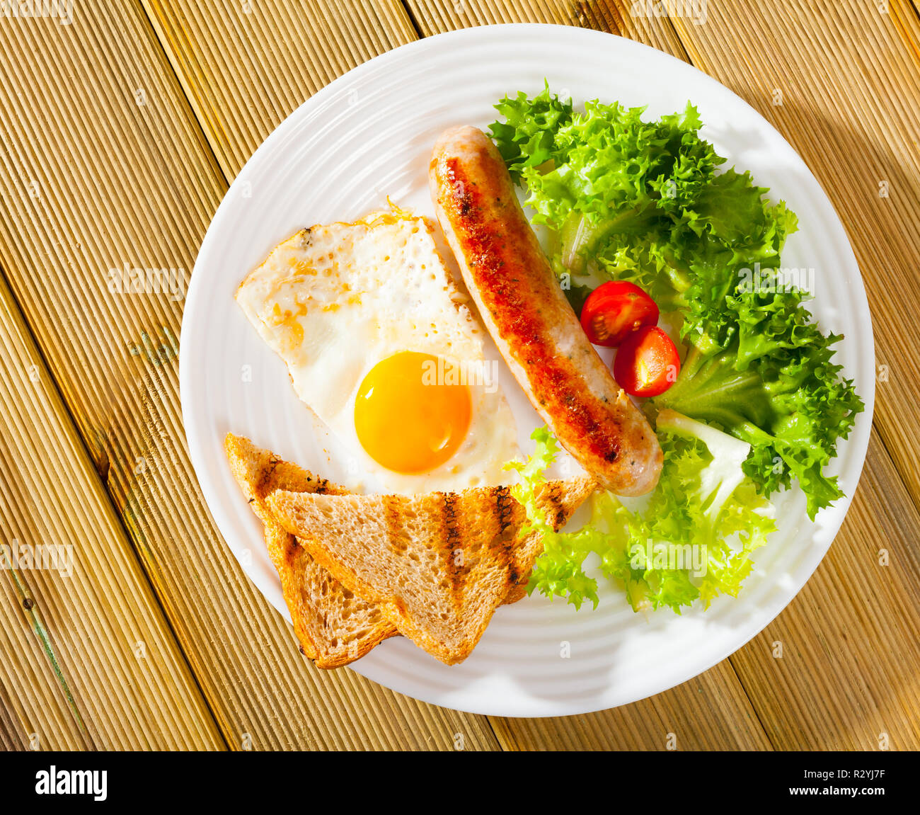 Top view of delicious breakfast of fried eggs with sausage, bread and ...