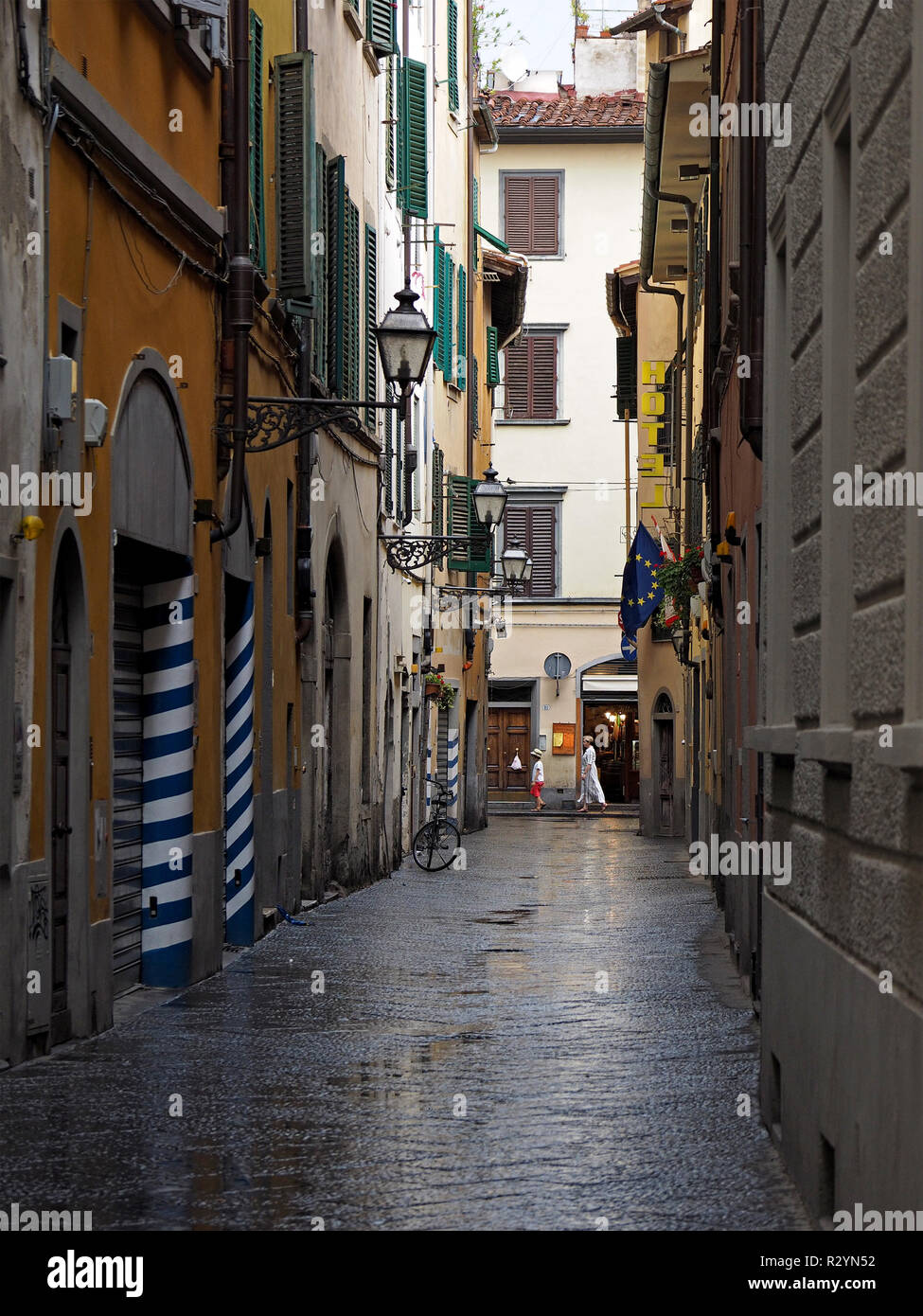street view of a narrow wet paved alleyway between typical tall ...