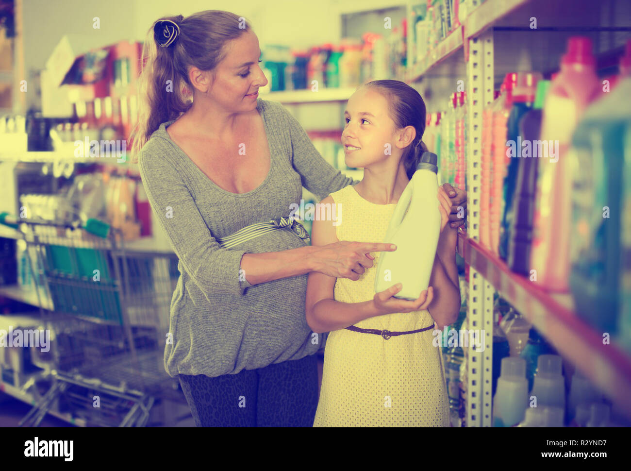 Smiling girl with mom choosing goods in chemistry rows in supermarket ...