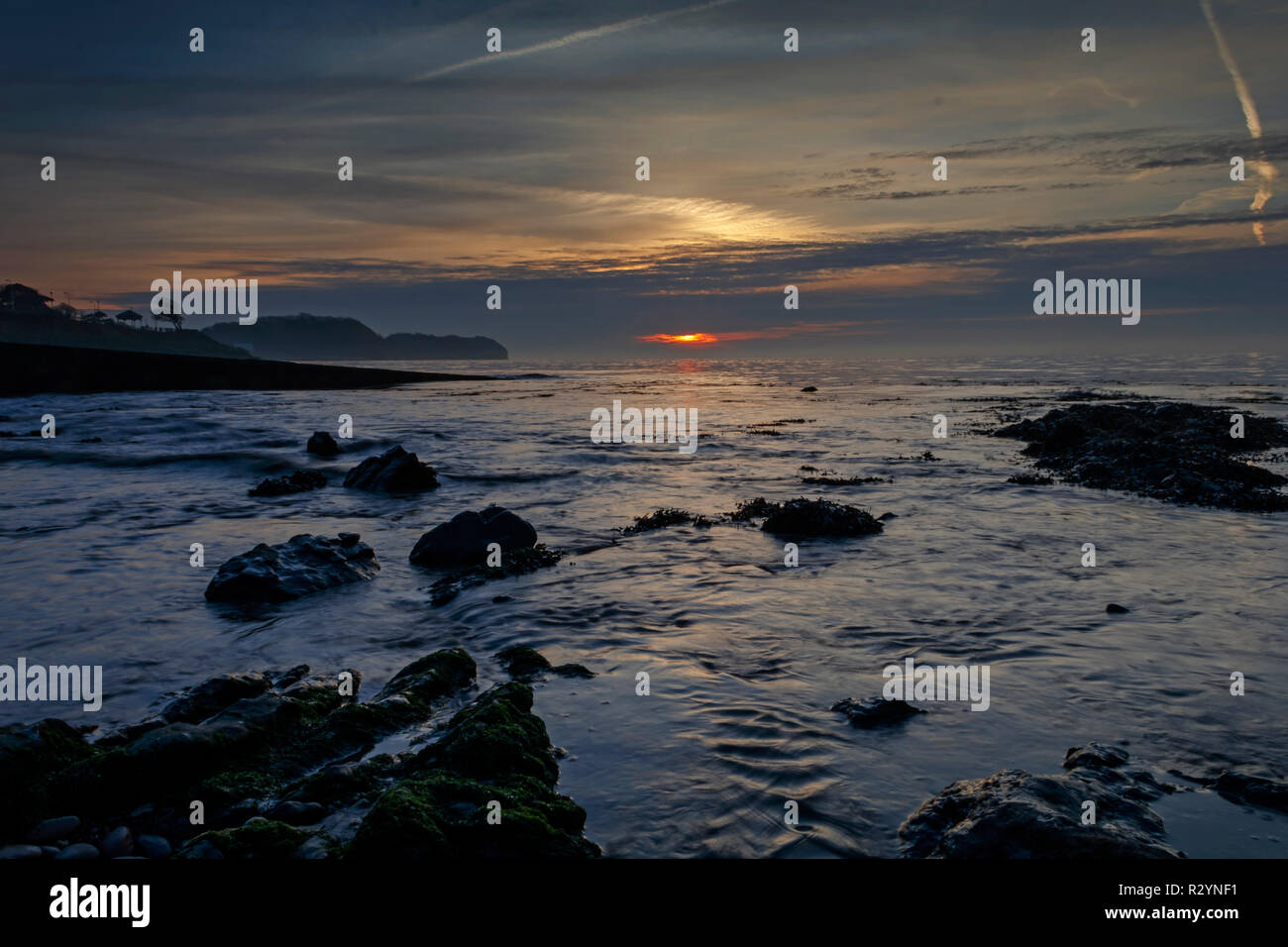 The sun setting over the horizon Stock Photo - Alamy