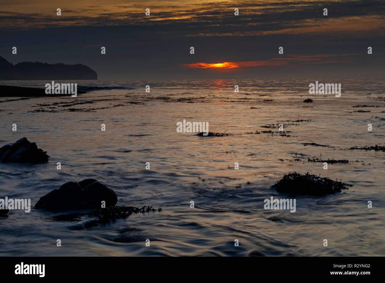 The sun setting over the horizon Stock Photo - Alamy