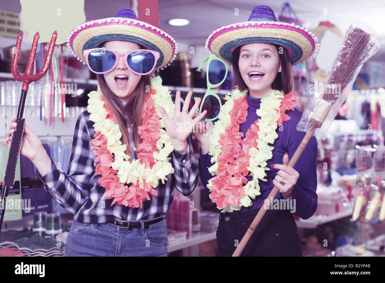 Two cheerful young female friends having fun in festival outfits store ...