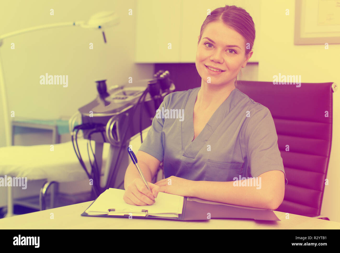 Young female doctor cosmetologist working with documents in modern ...