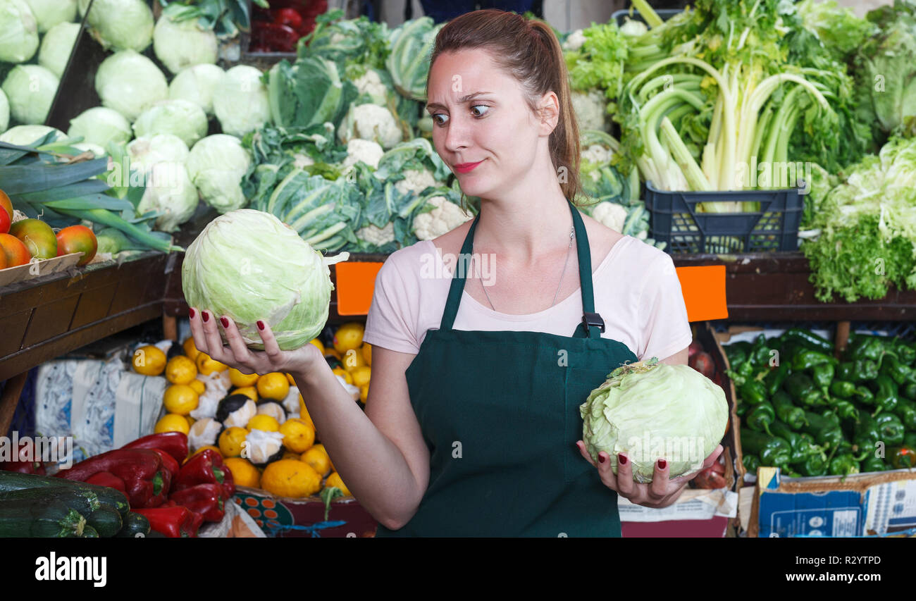 young seller female is holding green cabbage on her workplace in the ...