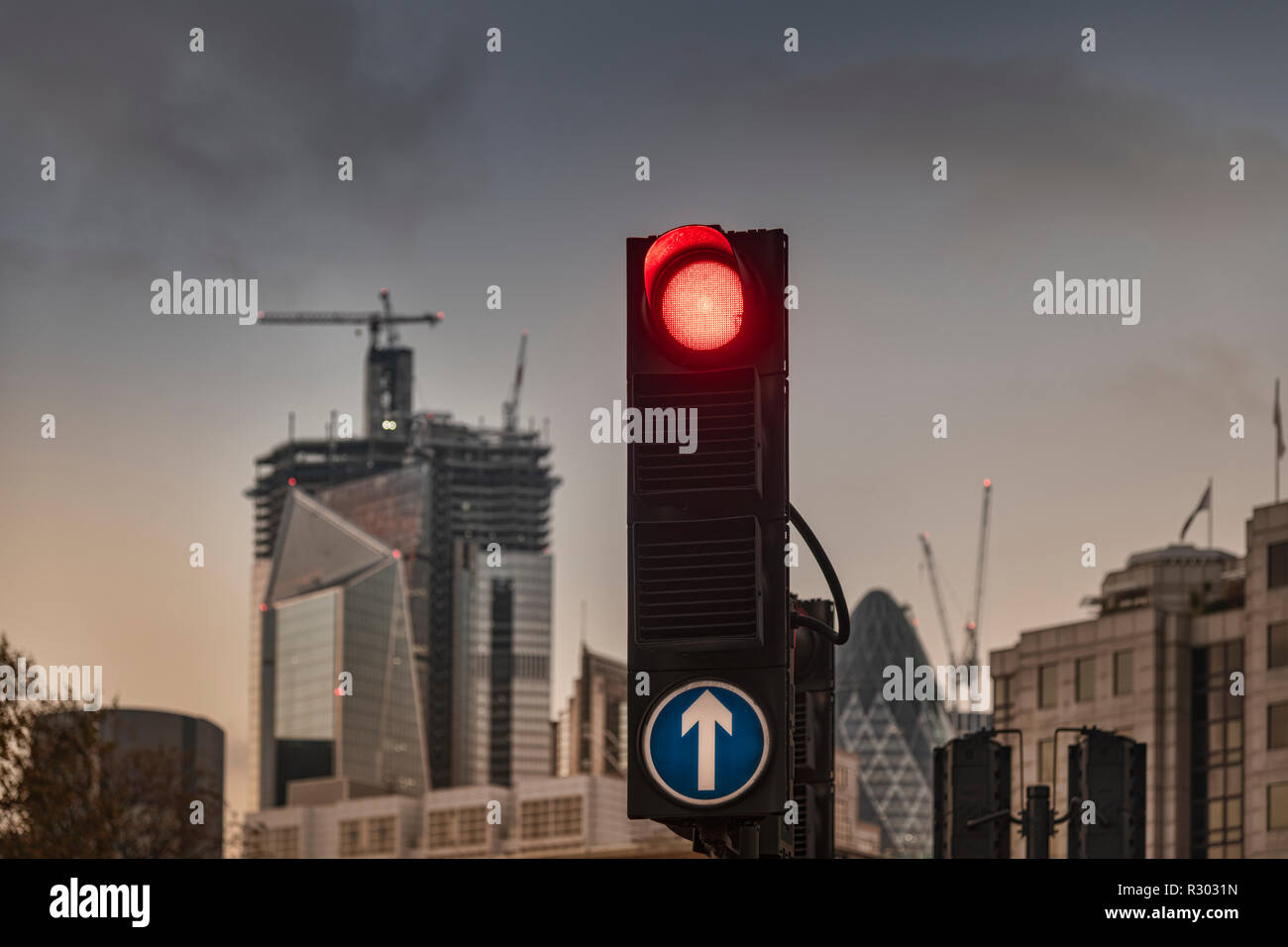 Red Traffic light with tall city buildings and construction site in the ...