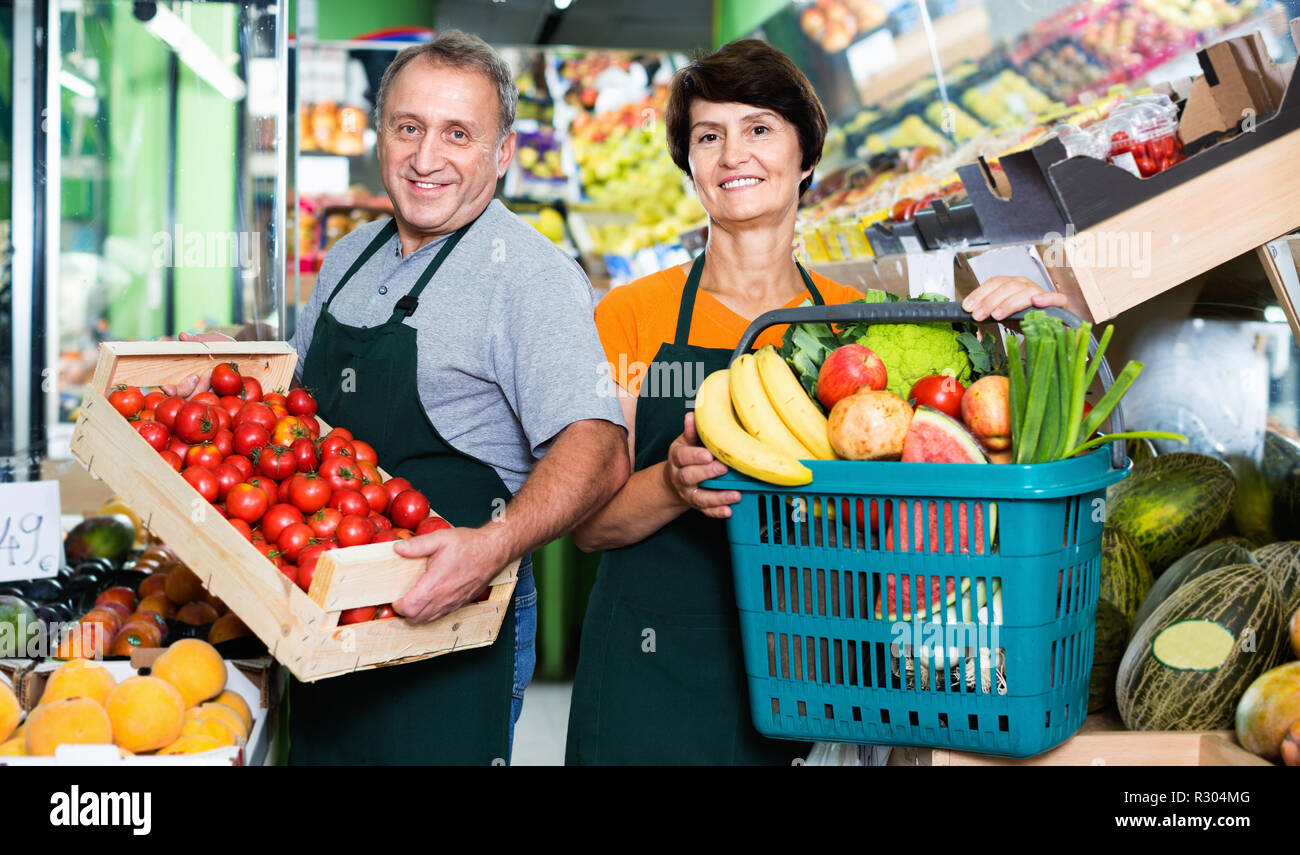 Smiling positive glad couple sellers is standing with basket with ...