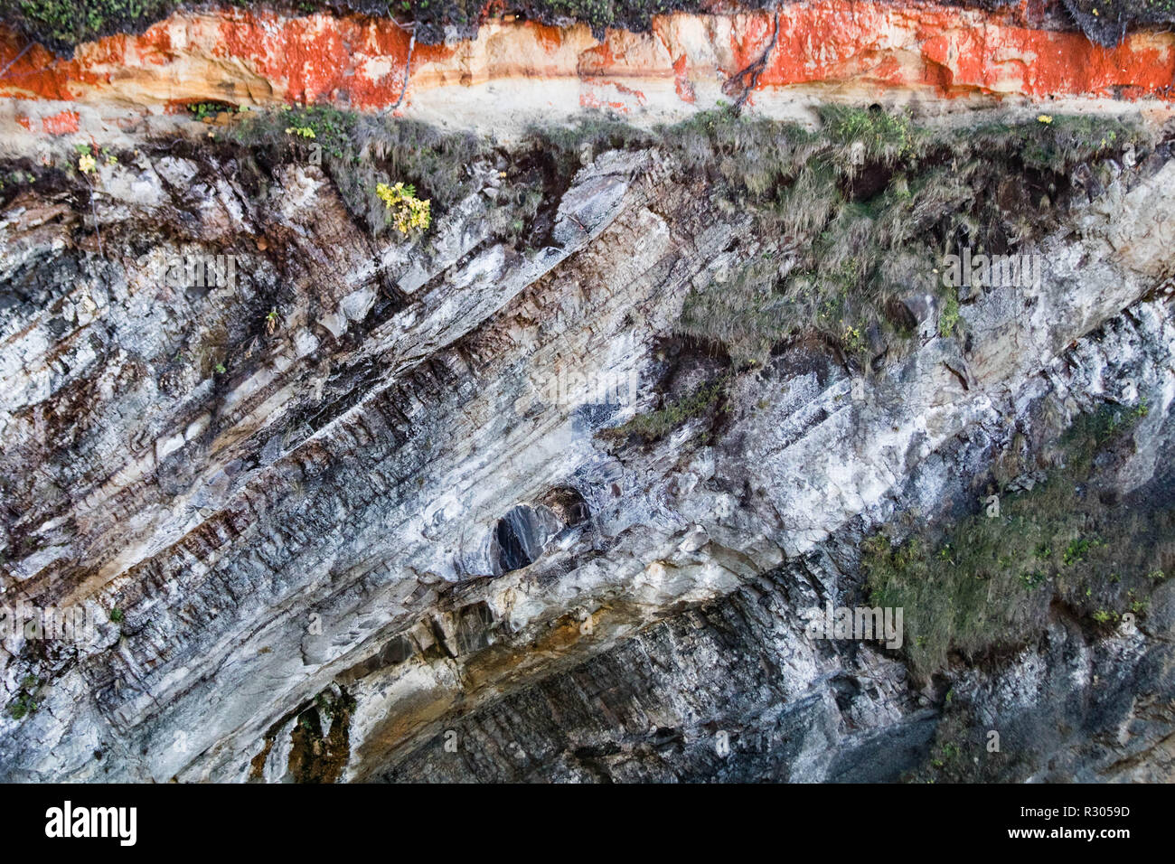 A vertical rock cliff face is topped with a burst of color as sandy ...