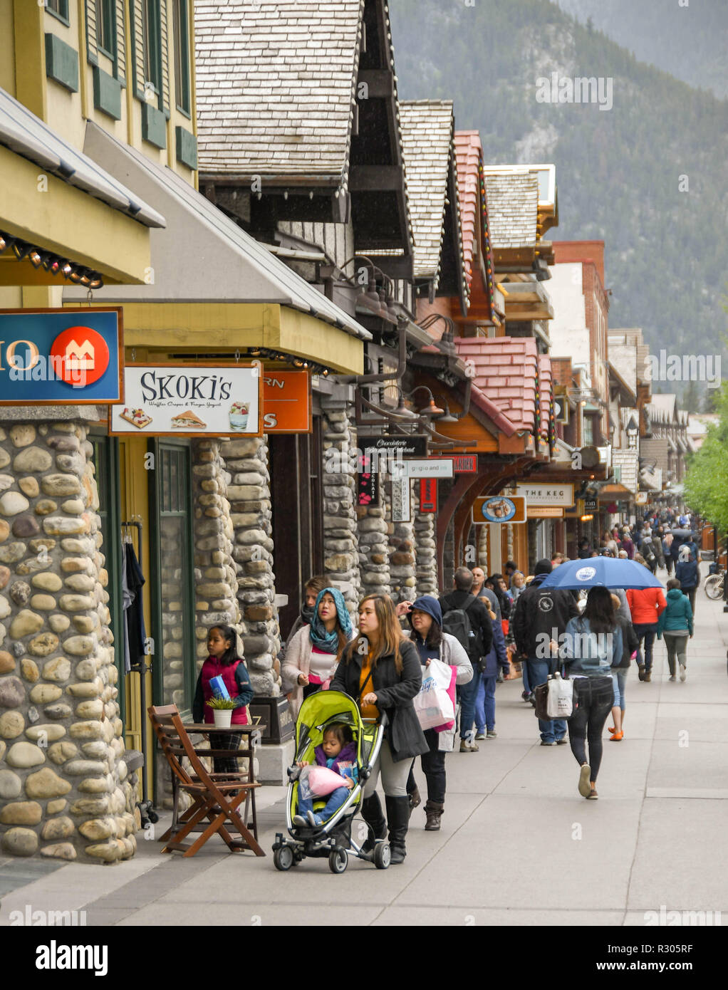 BANFF, AB, CANADA - JUNE 2018: Tourists strolling past shops in the ...