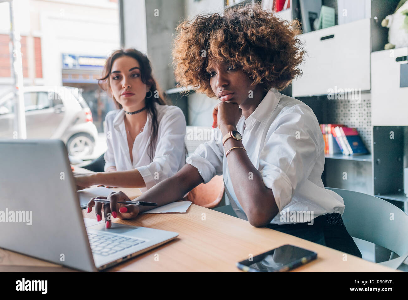 two young women of creative team working indoor using laptop computer ...