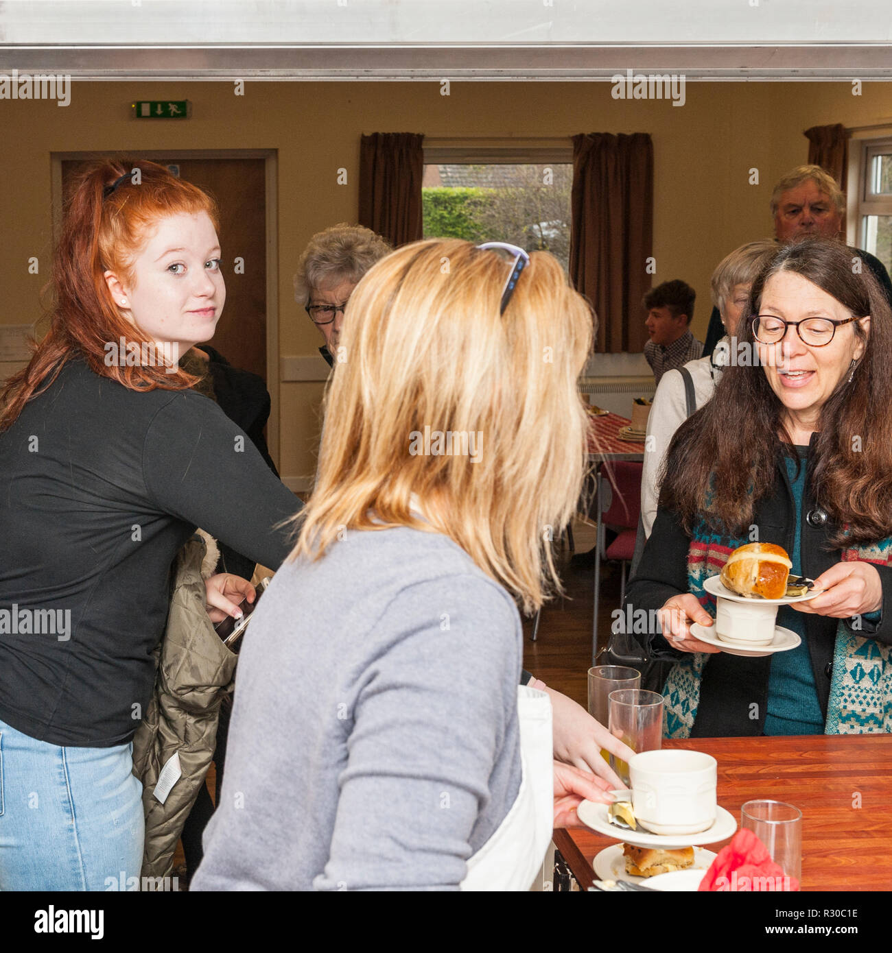 A woman serving hot cross buns and drinks in a Uk village hall Stock ...