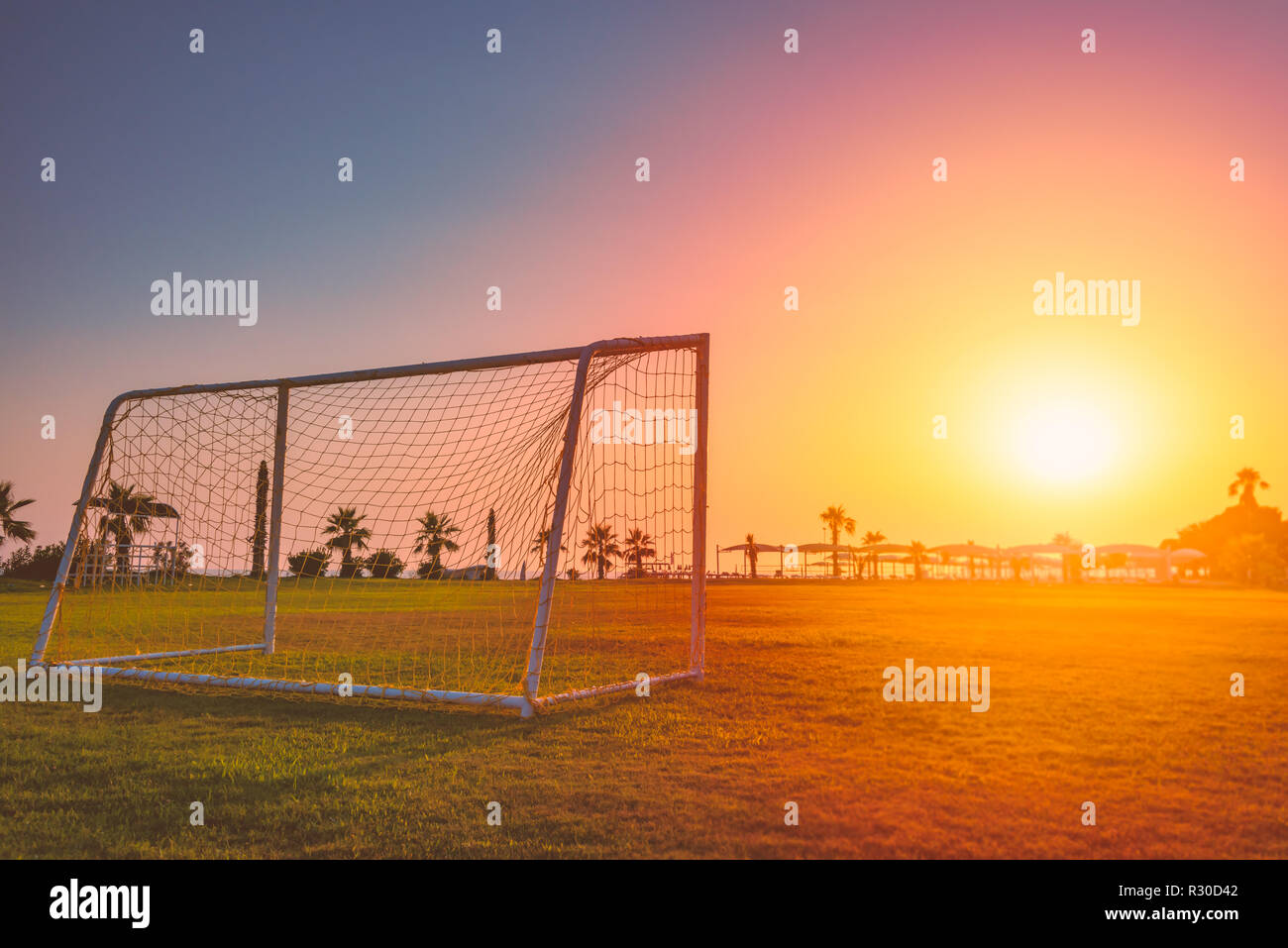 Football goal with net at sunset in tropical climate. Green field ...