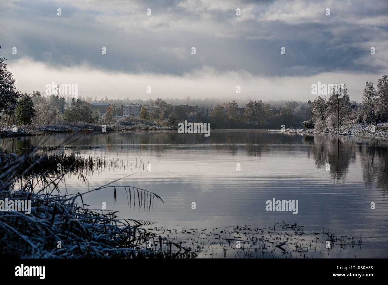 cold and calm morning view by the lake with first snow in winter with ...