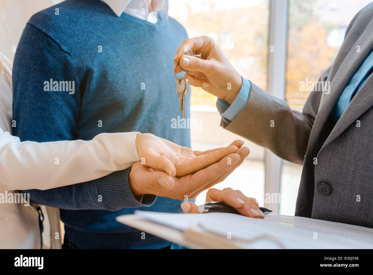 Realtor woman giving house keys to couple, closeup Stock Photo - Alamy