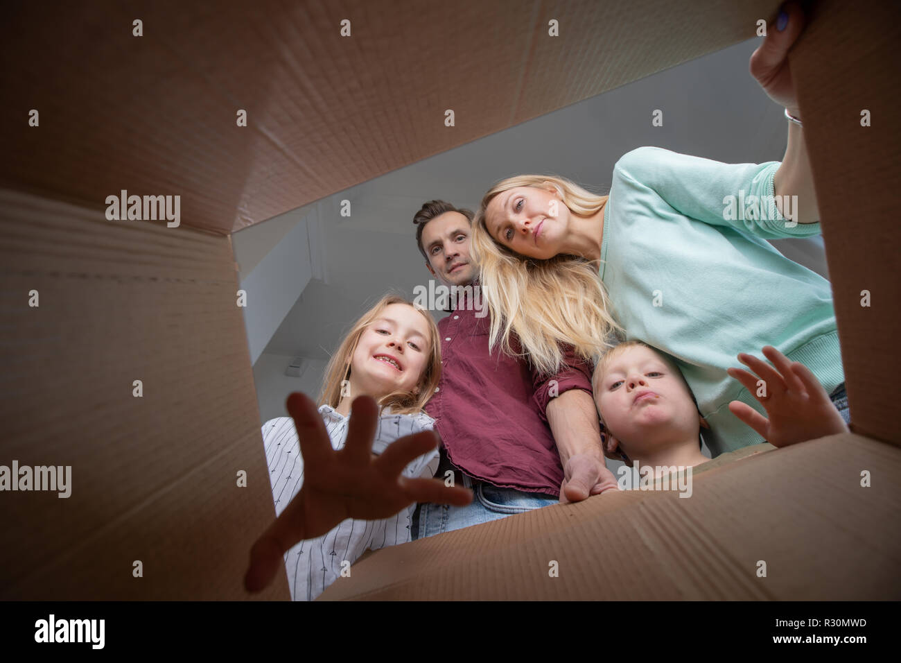 Image of cheerful parents and children looking inside cardboard box in ...