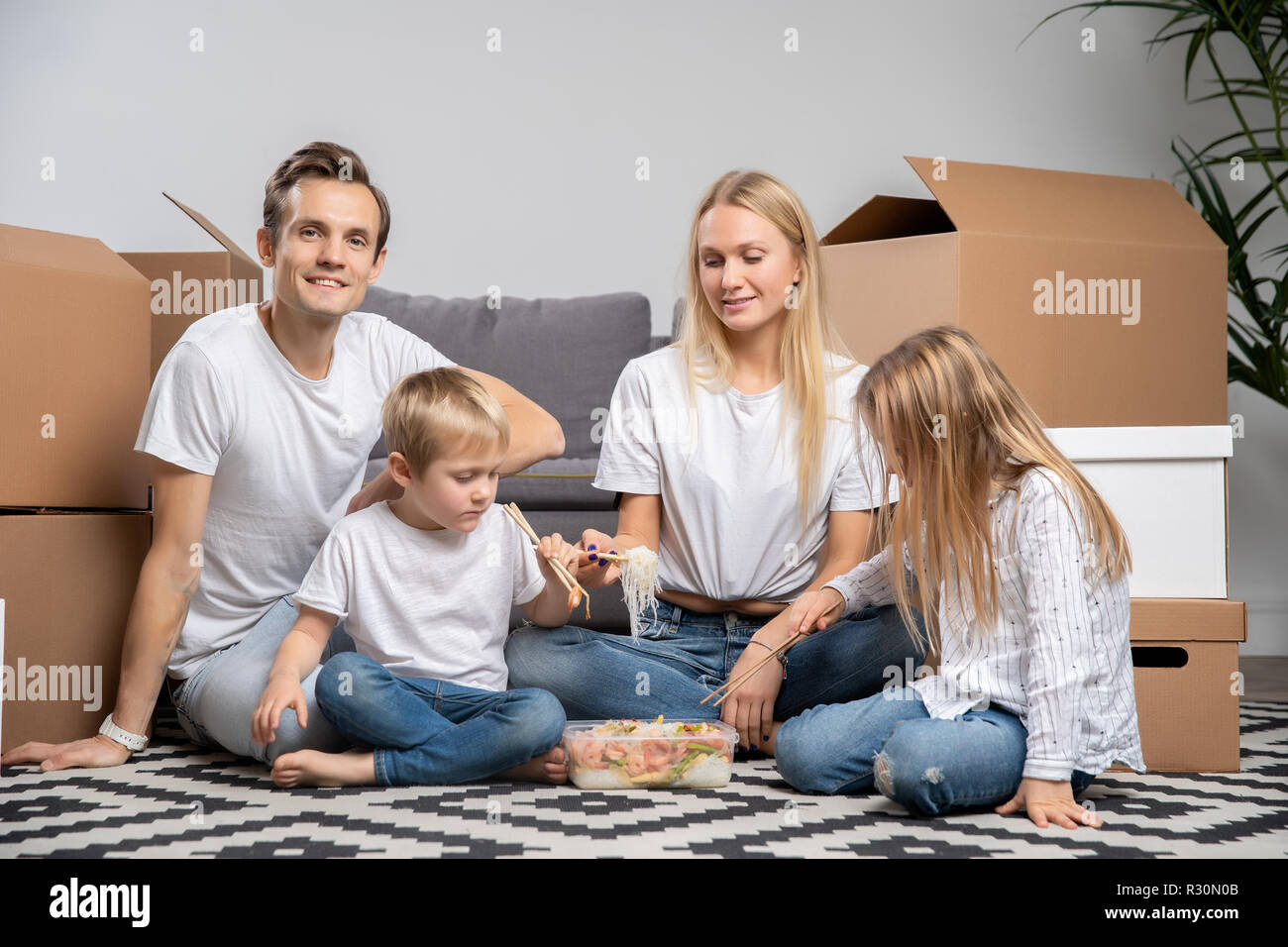 Photo of couple with children eating rice with shrimps sitting on floor ...