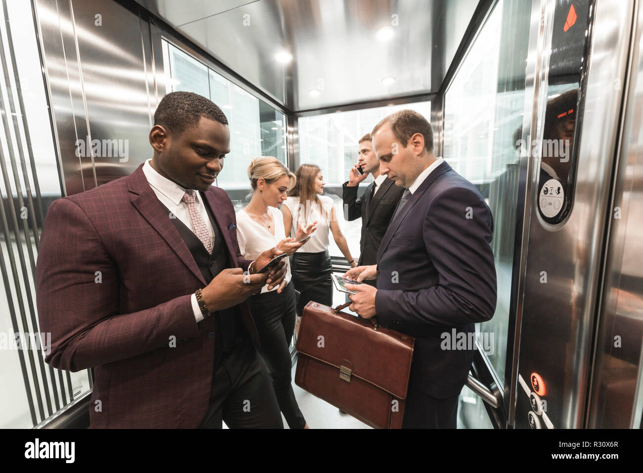 successful and young businessmen in the elevator business center rides ...