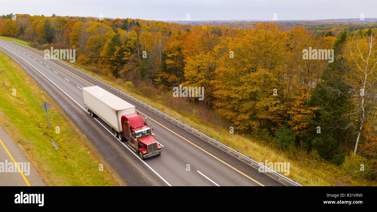 A big semi truck rig enjoys fall color in New England on the open road ...