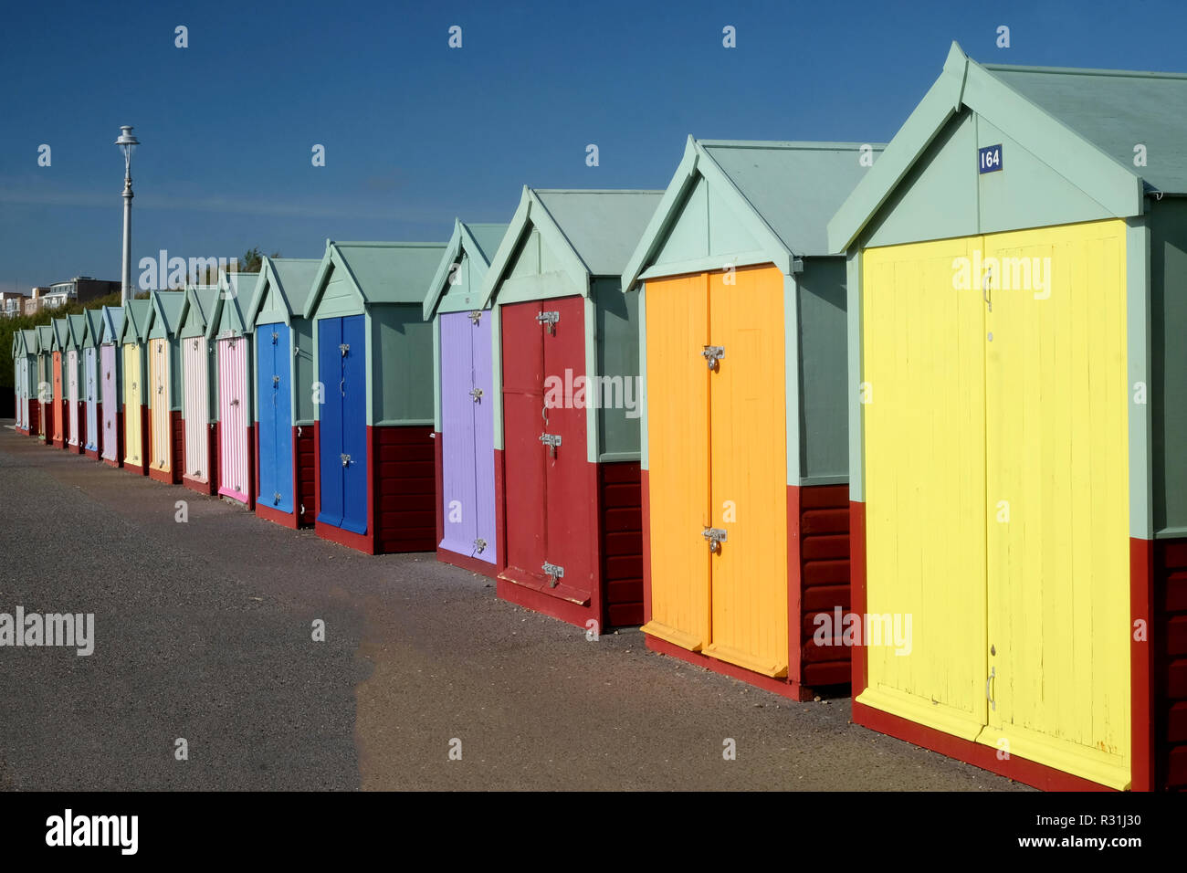 A line of 16 Beach huts with different multicoloured doors on a ...